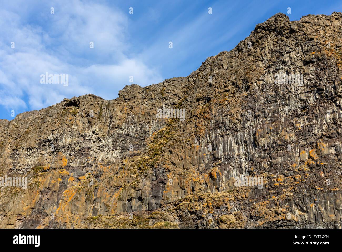 Vertical volcanic rock formations and cliffs overgrown with moss in ...