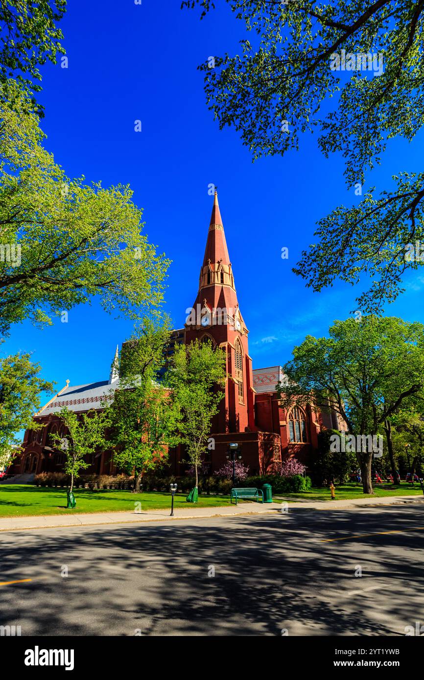 A large red church with a steeple and a green bench in front of it. The ...