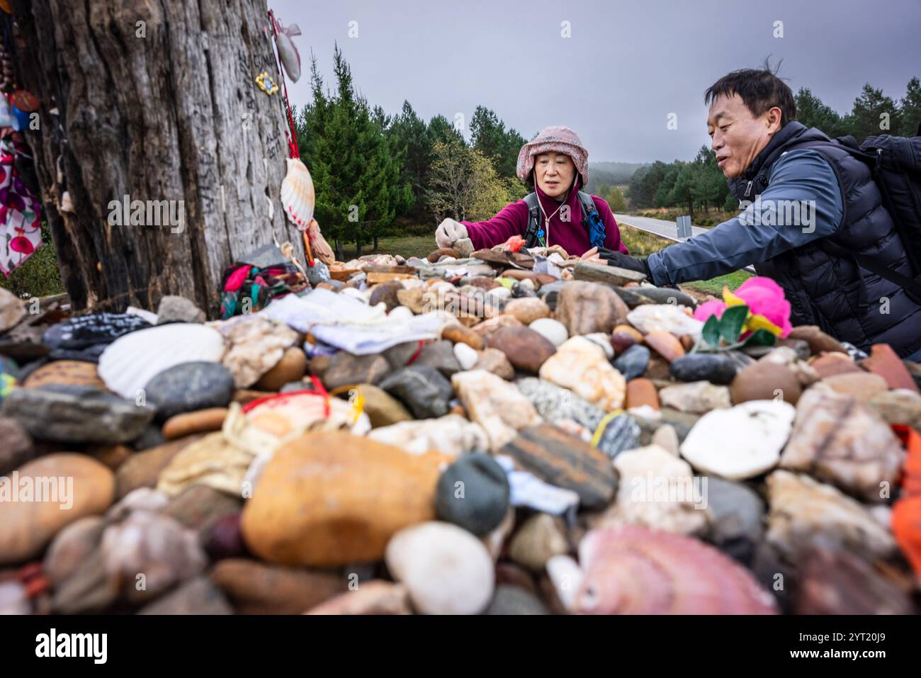 Pilgrim on the Camino de Santiago offering votive stones and offerings ...