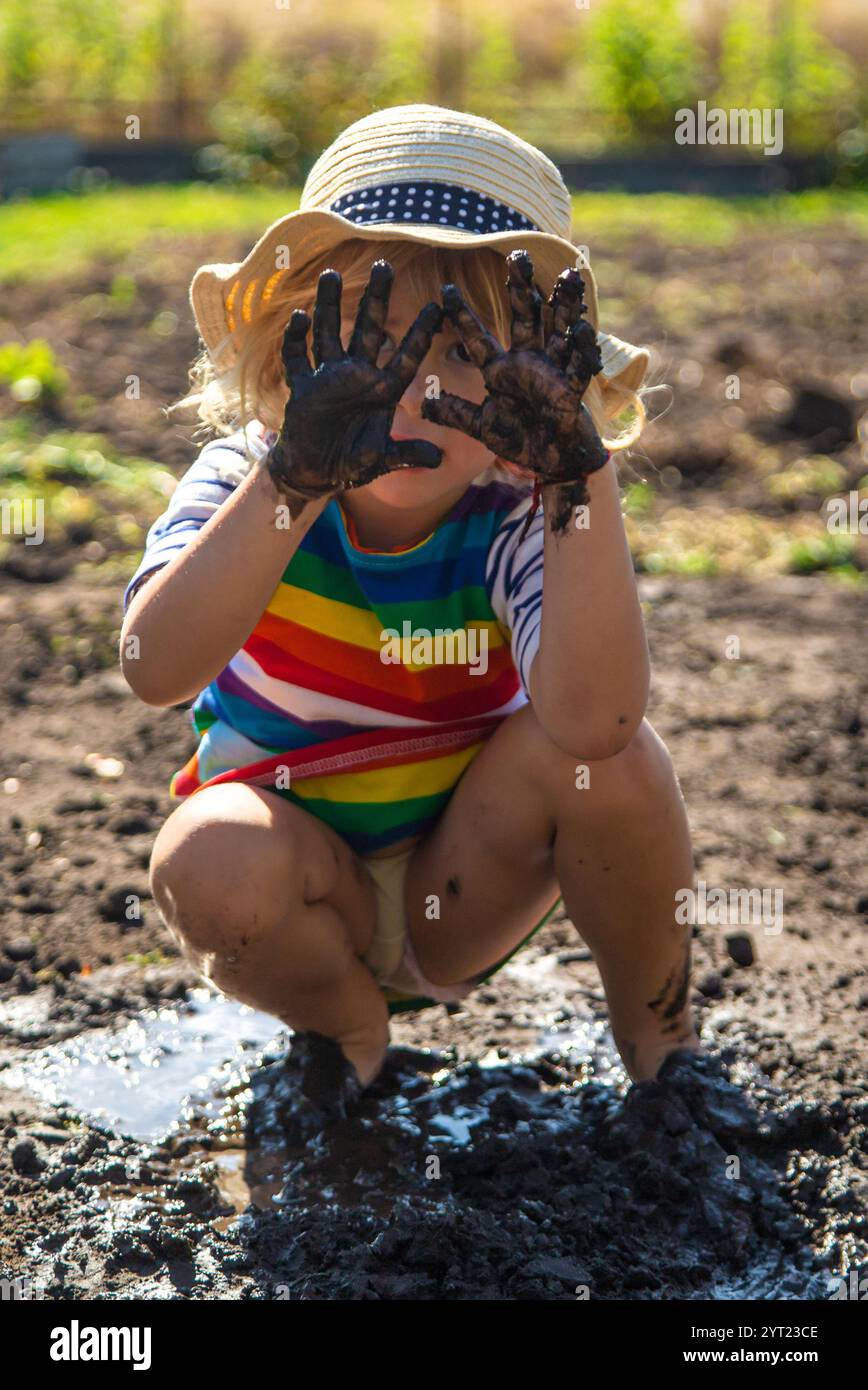 Child playing in mud. Selective focus. Kid Stock Photo - Alamy