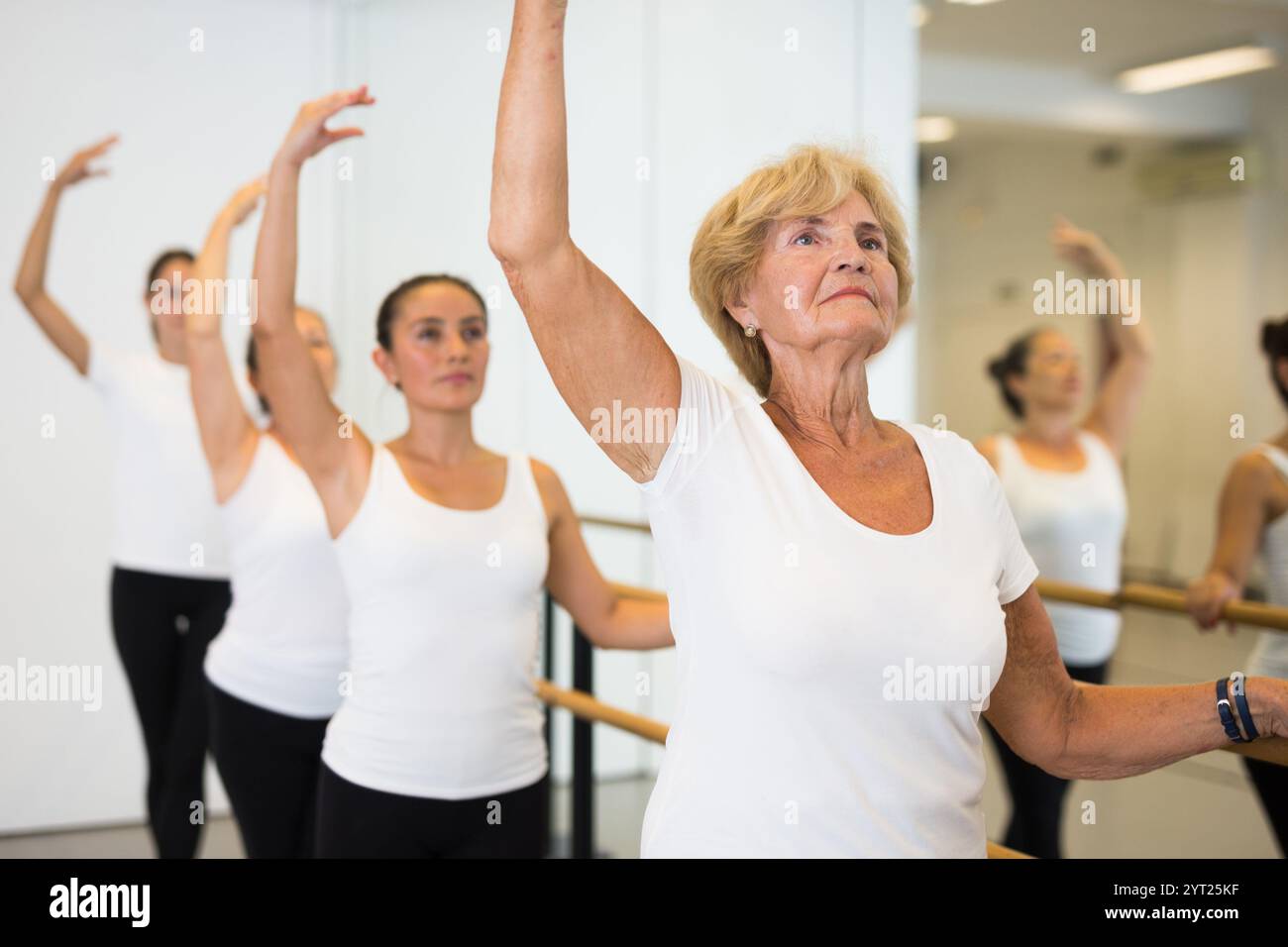 Group of ballerina standing with one hand on barre and reaching over ...