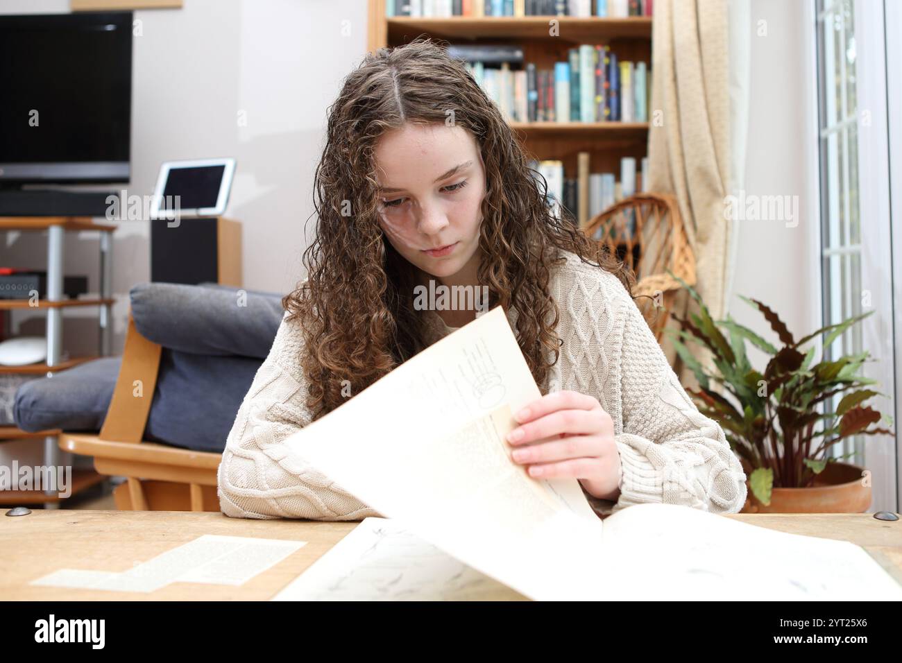 Teenage girl reading revising from a book turning pages studying ...