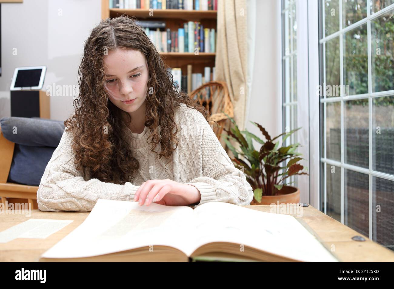 Teenage girl reading revising from a book turning pages studying ...