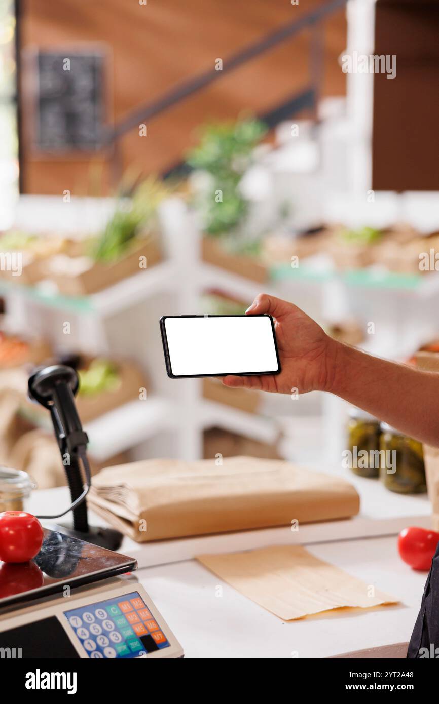 Mobile phone with a white screen held up above a counter in a grocery ...