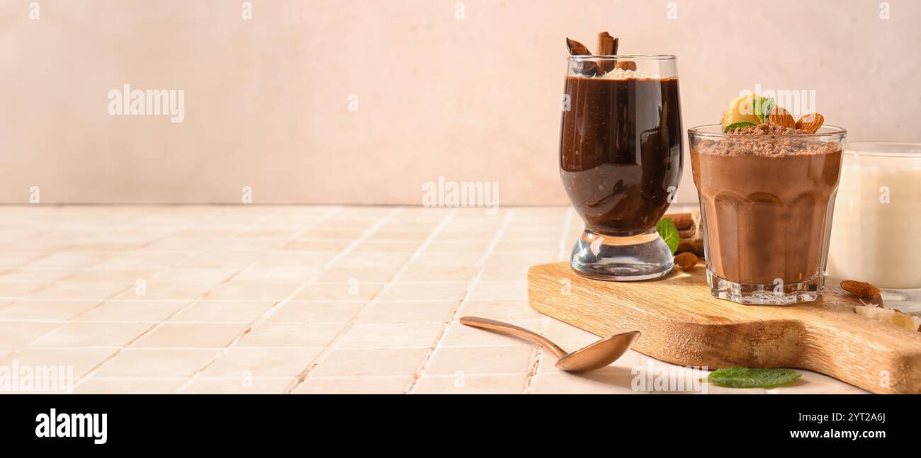 Board with glasses of delicious chocolate pudding on tile table. Banner ...
