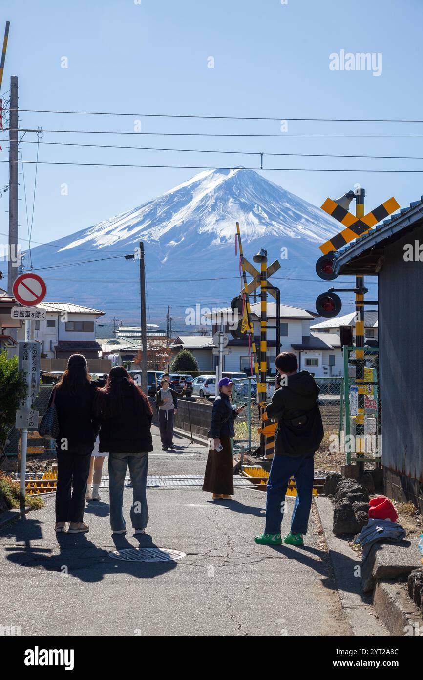 Tourists on a small road and train crossing near Kawaguchiko Station in ...