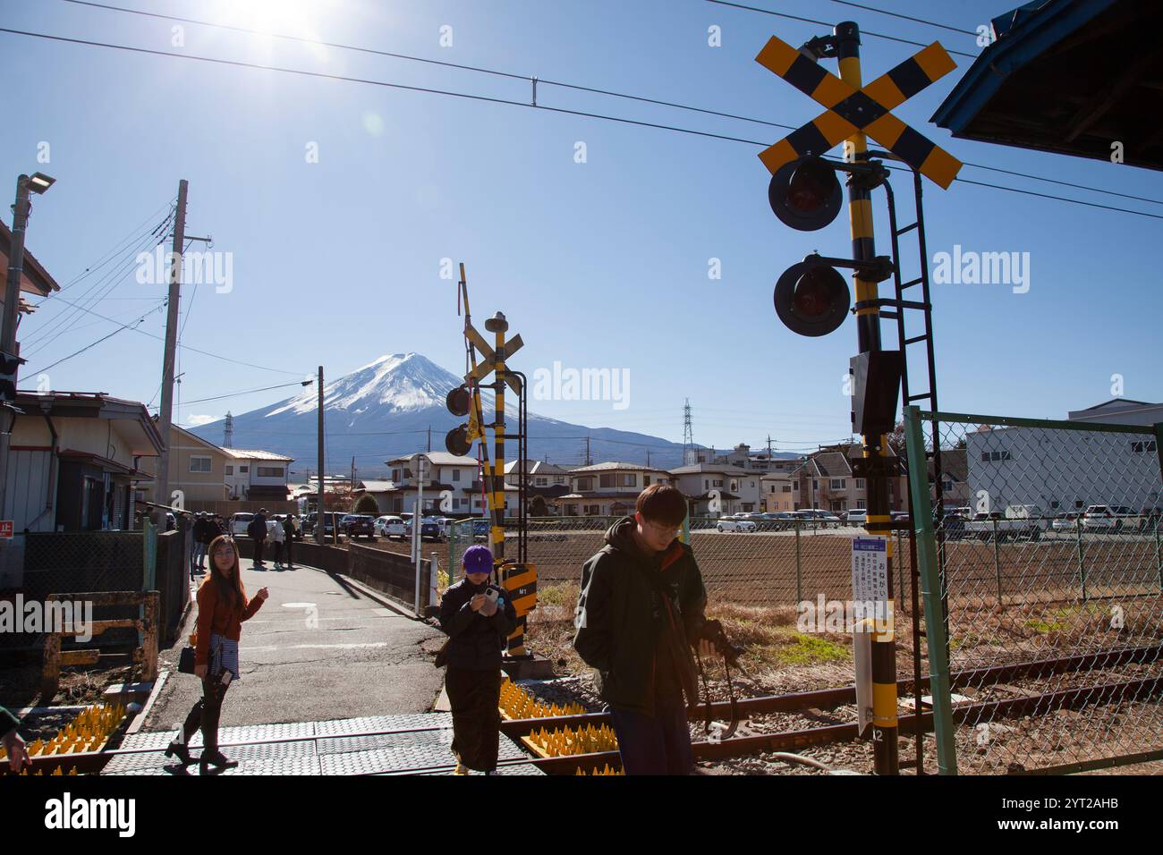 Tourists on a small road and train crossing near Kawaguchiko Station in ...