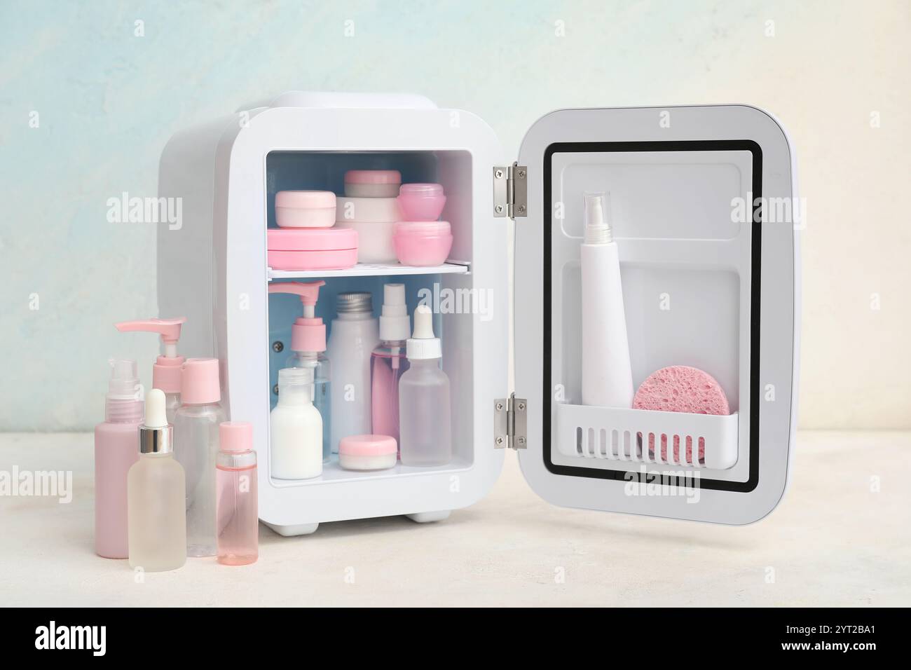 Small cosmetic refrigerator with cosmetic products on light blue ...