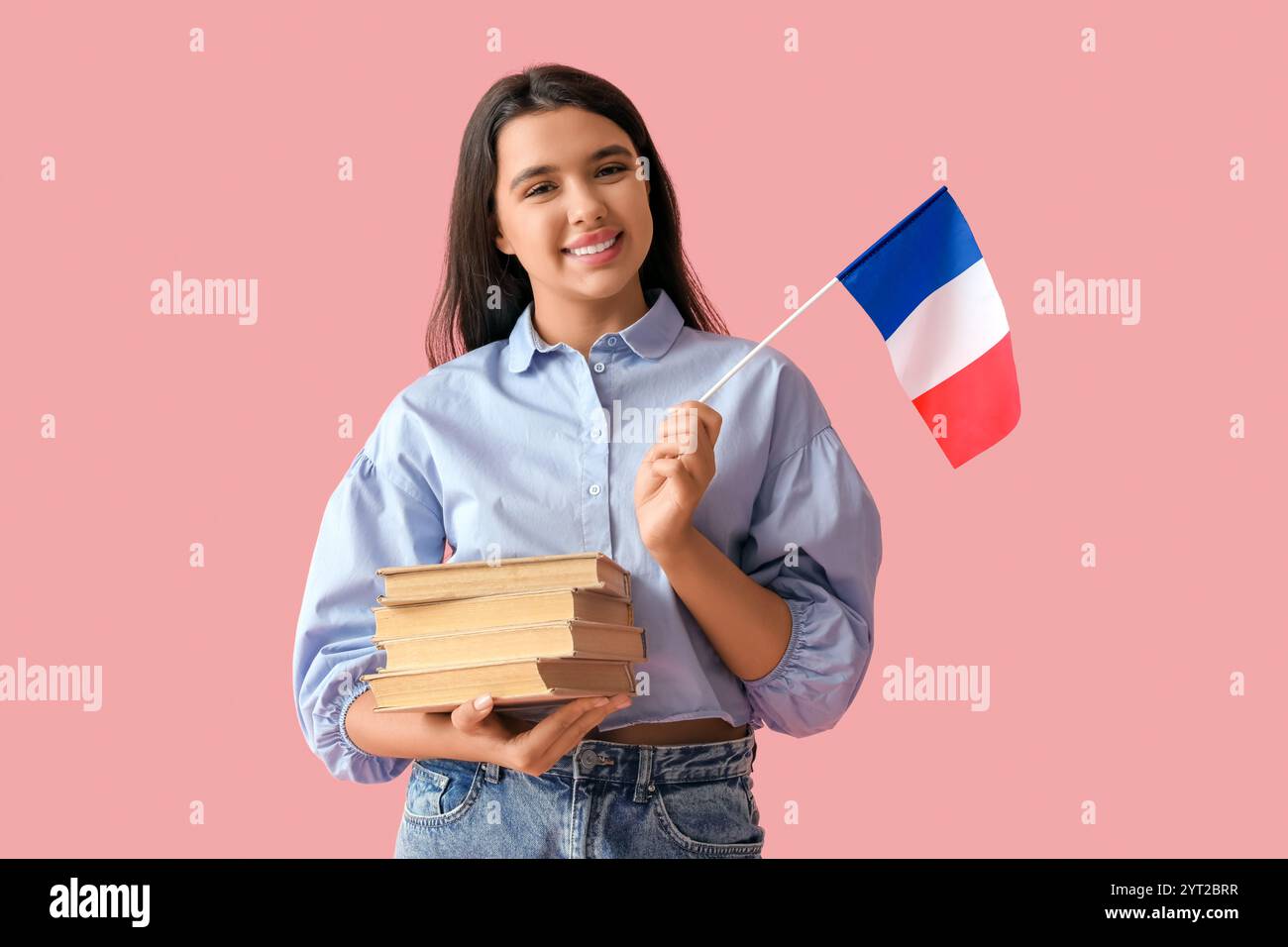 Female French language teacher with books and flag on pink background ...