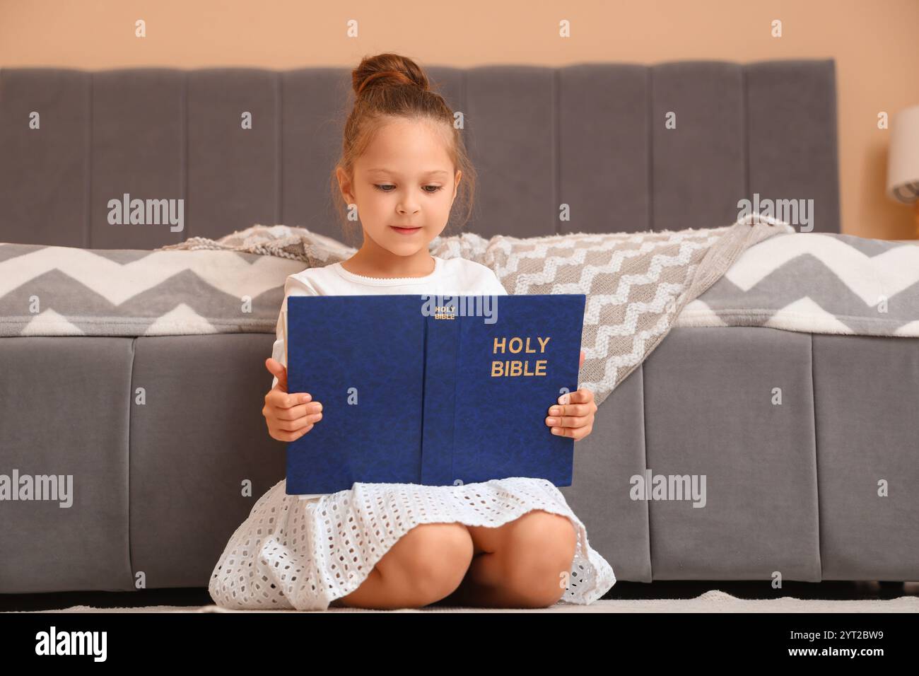 Cute little girl reading Holy Bible at home Stock Photo - Alamy