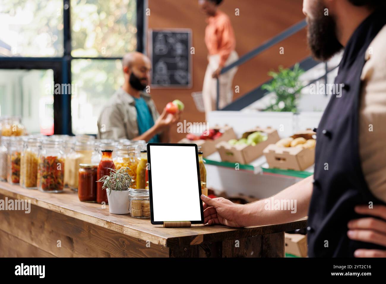 Male shopkeeper checks out a tablet placed on table that is displaying ...