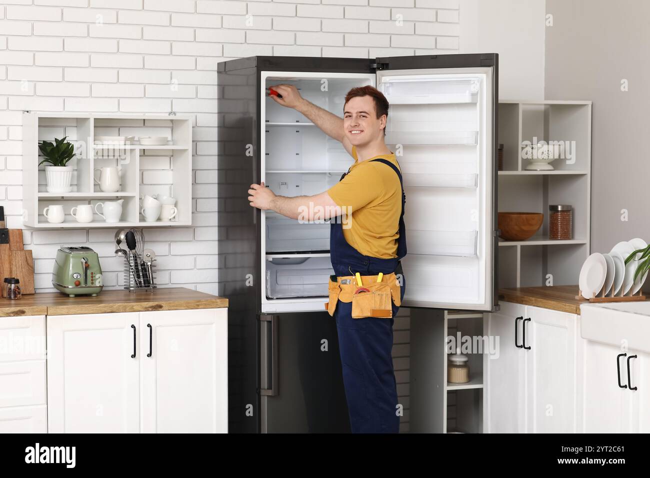 Happy male worker repairing refrigerator in kitchen Stock Photo - Alamy