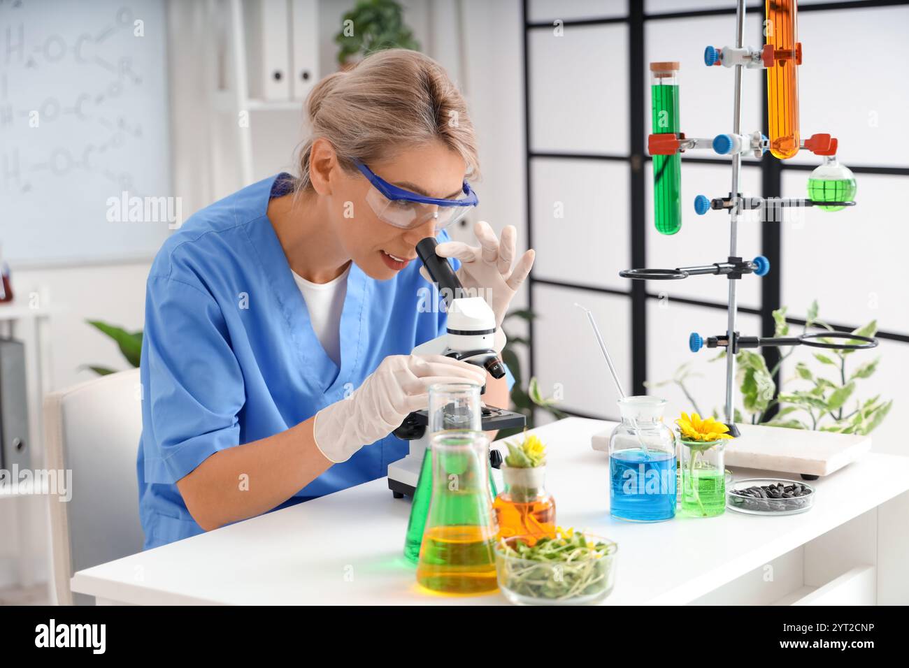Happy female scientist with flasks of samples and microscope testing ...