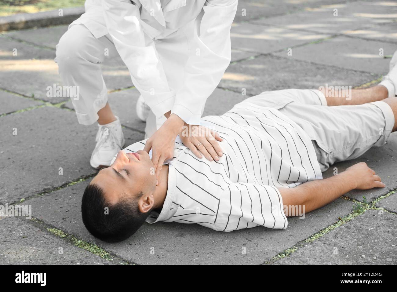 Female doctor doing CPR on unconscious man having heart attack in park ...