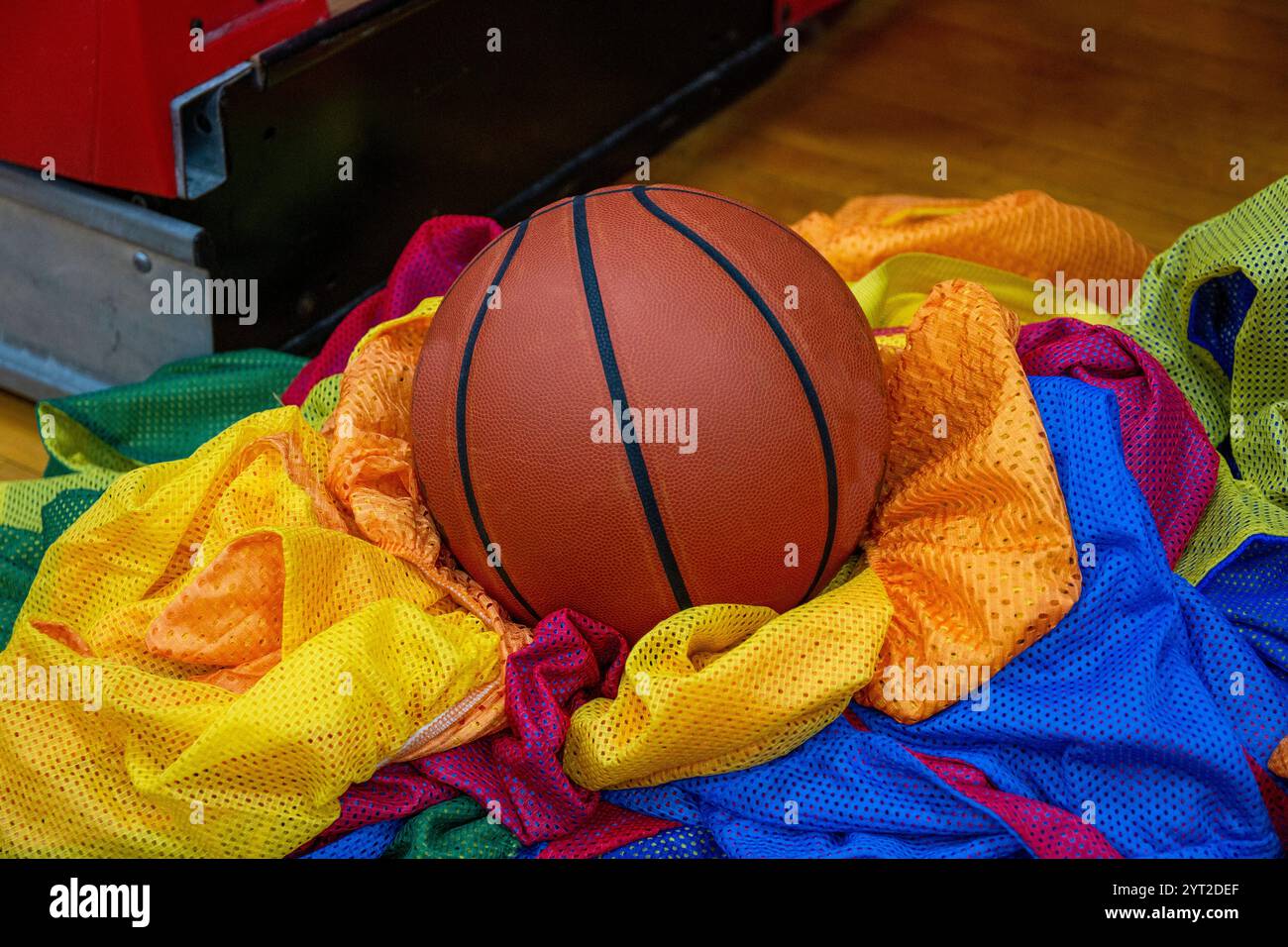 A basketball rests on a pile of vibrant practice nets, creating a ...