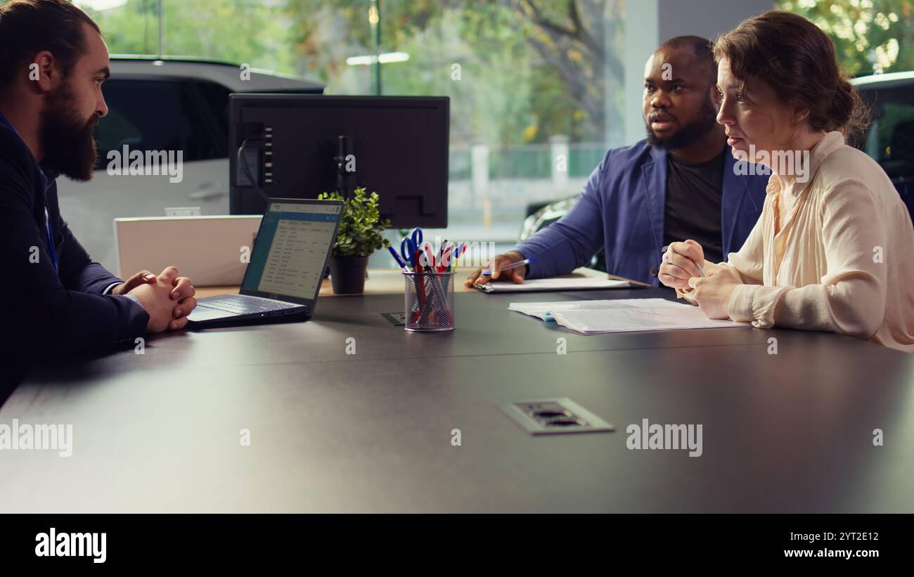 Dealership salesman looking over appointment list on laptop spreadsheet ...