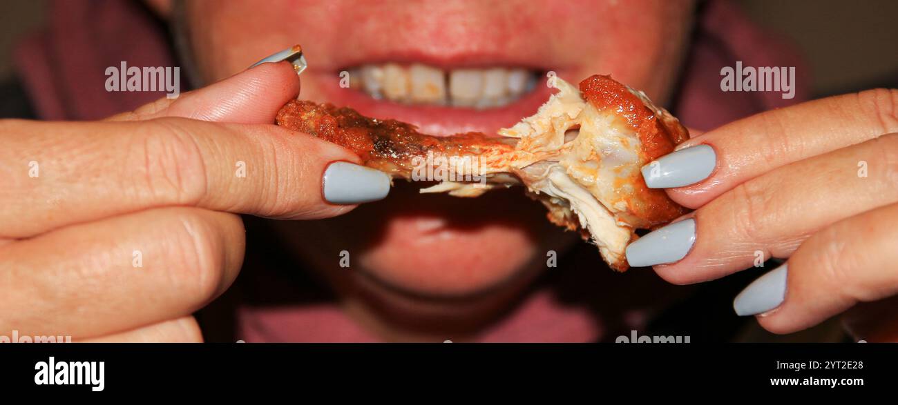 Close up of a women biting a buffalo chicken wing while eating in a ...