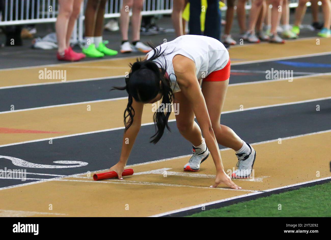 Athlete crouches down to start a relay race while competing at an ...