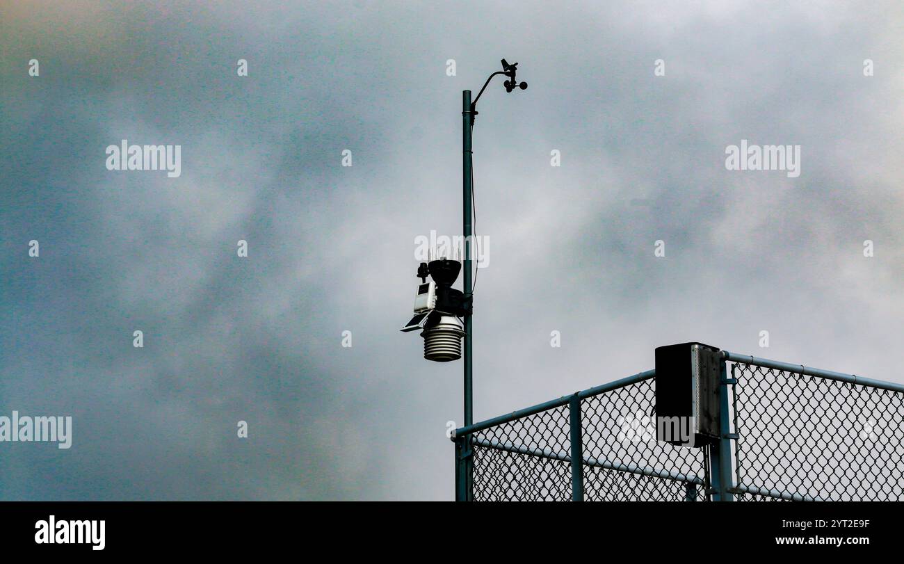 A weather monitoring station atop a pole records data while observing ...