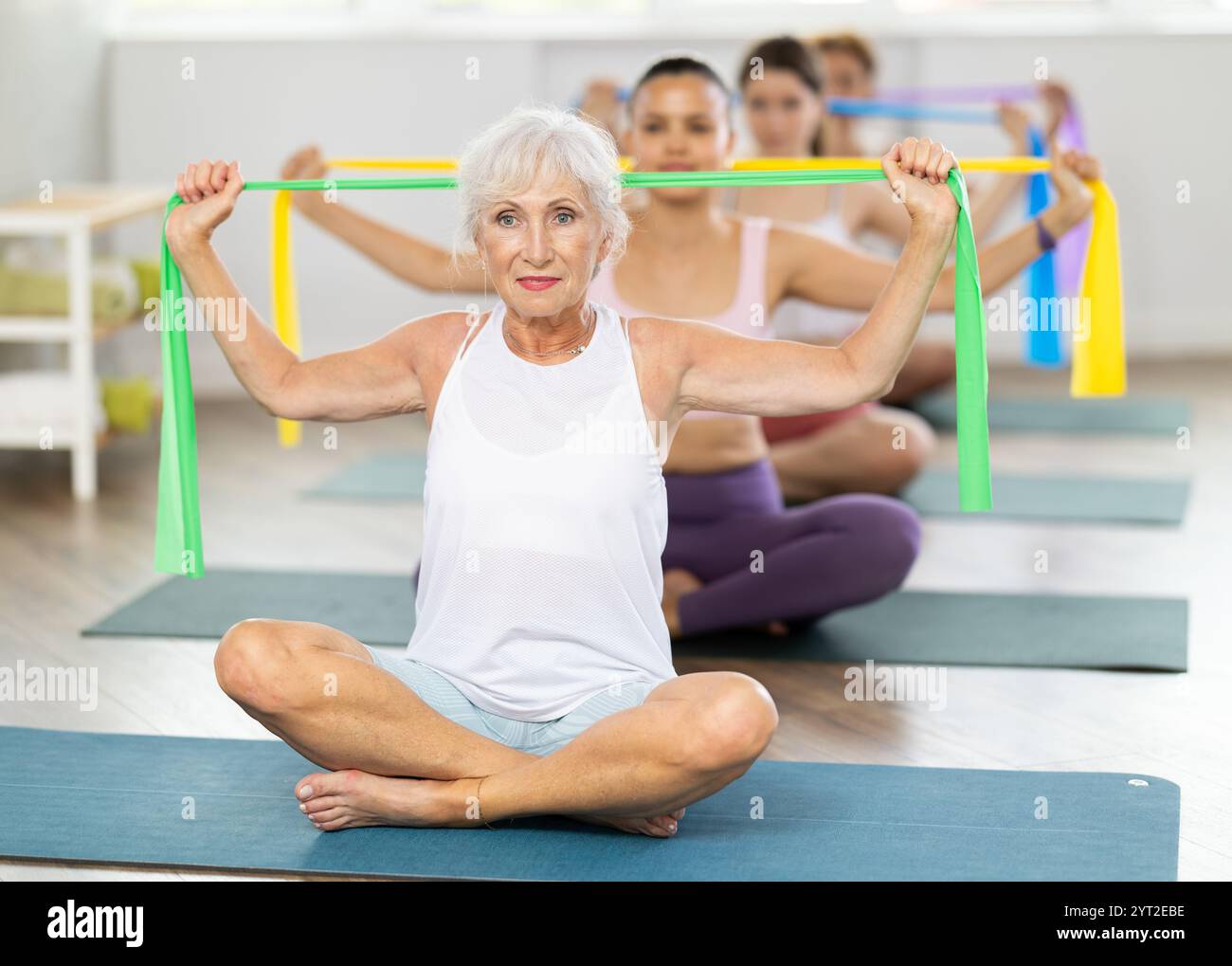 Senior lady performing exercises with resistance band in pilates class ...