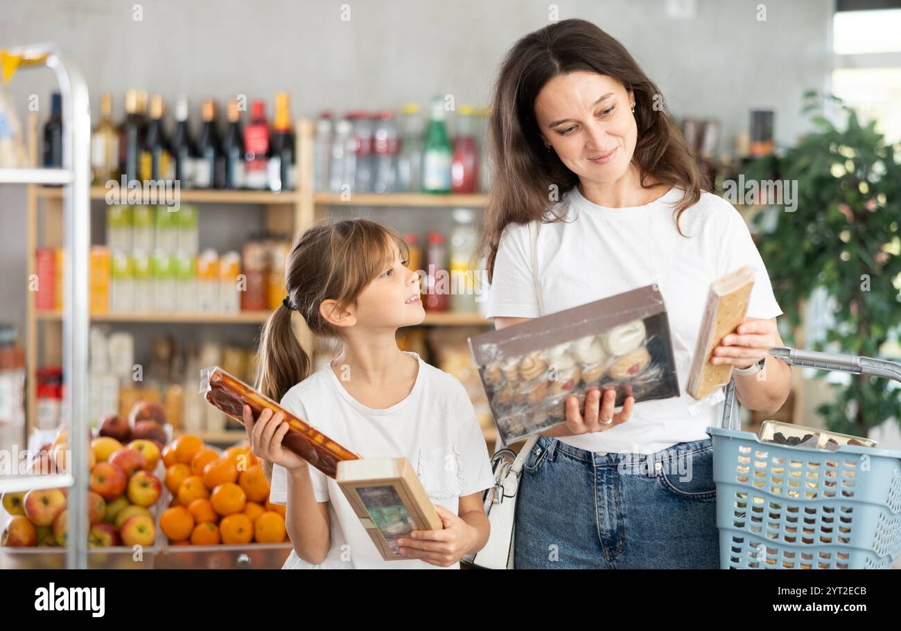 Child girl with mother choose consider sweets snacks Stock Photo - Alamy