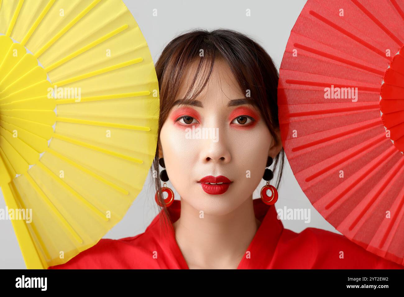 Beautiful young geisha in traditional clothes with fans on grey ...