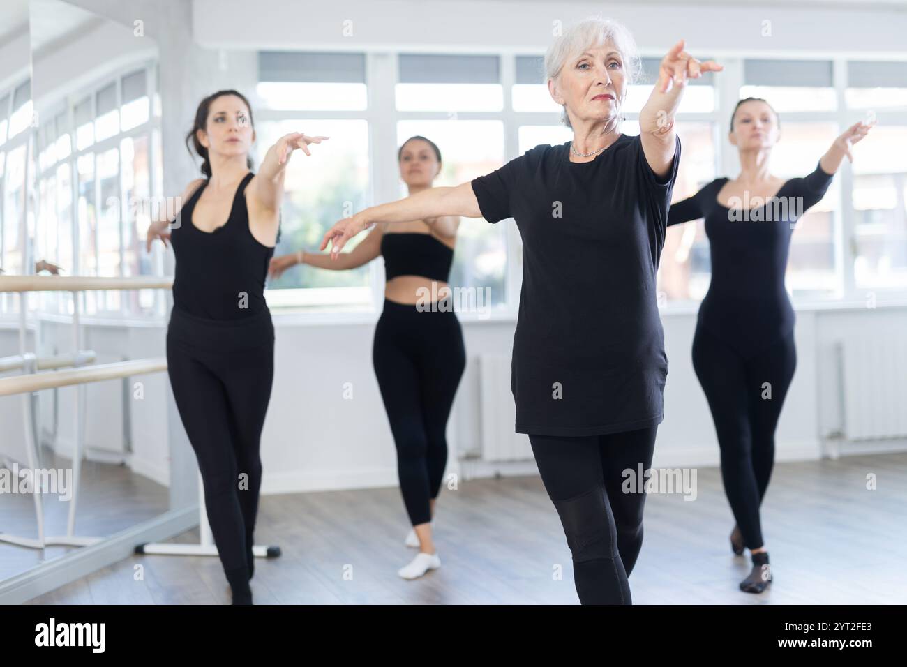 Graceful women of different ages practice various ballet movements in ...