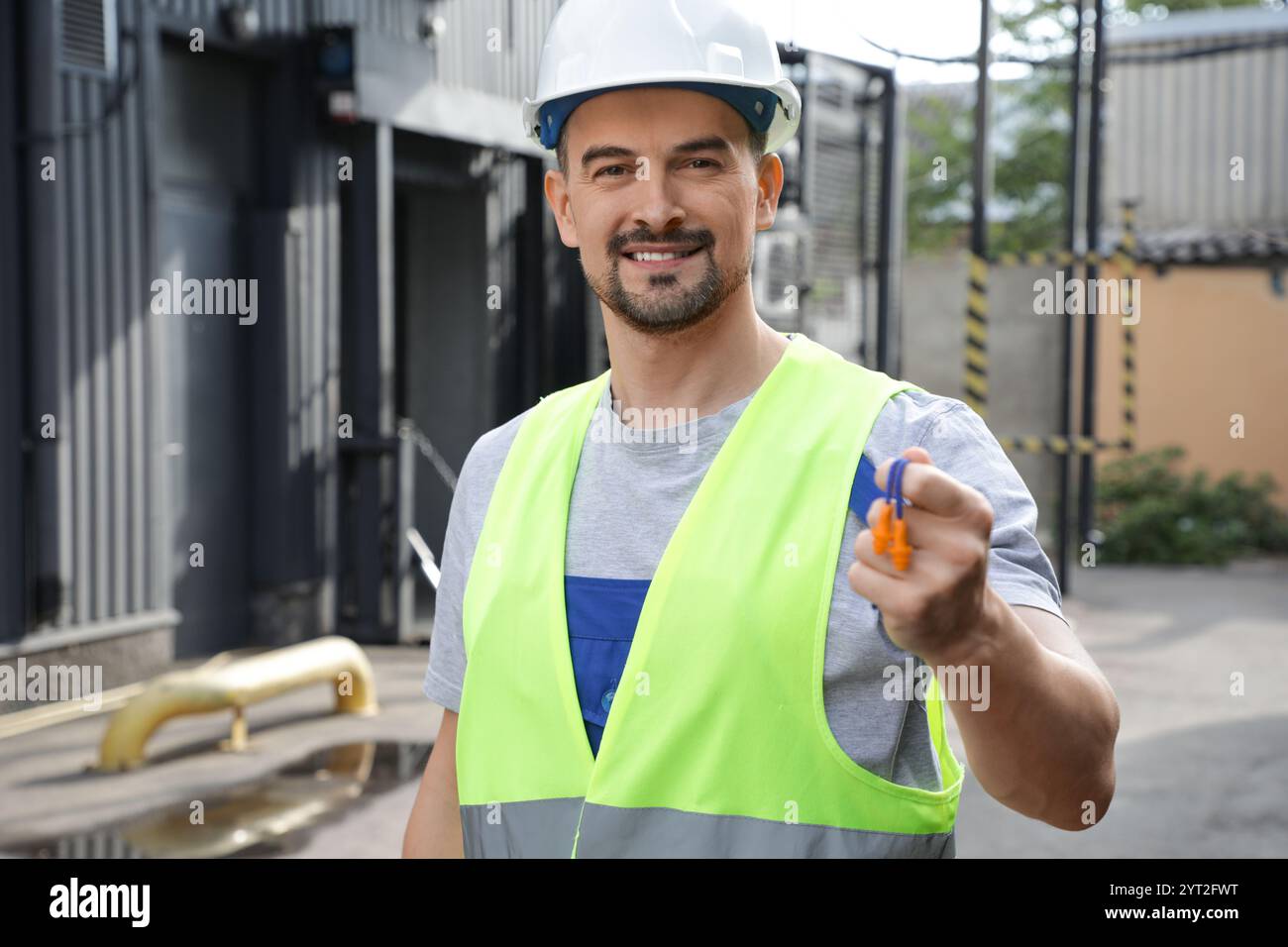 Male builder with earplugs outdoors Stock Photo - Alamy