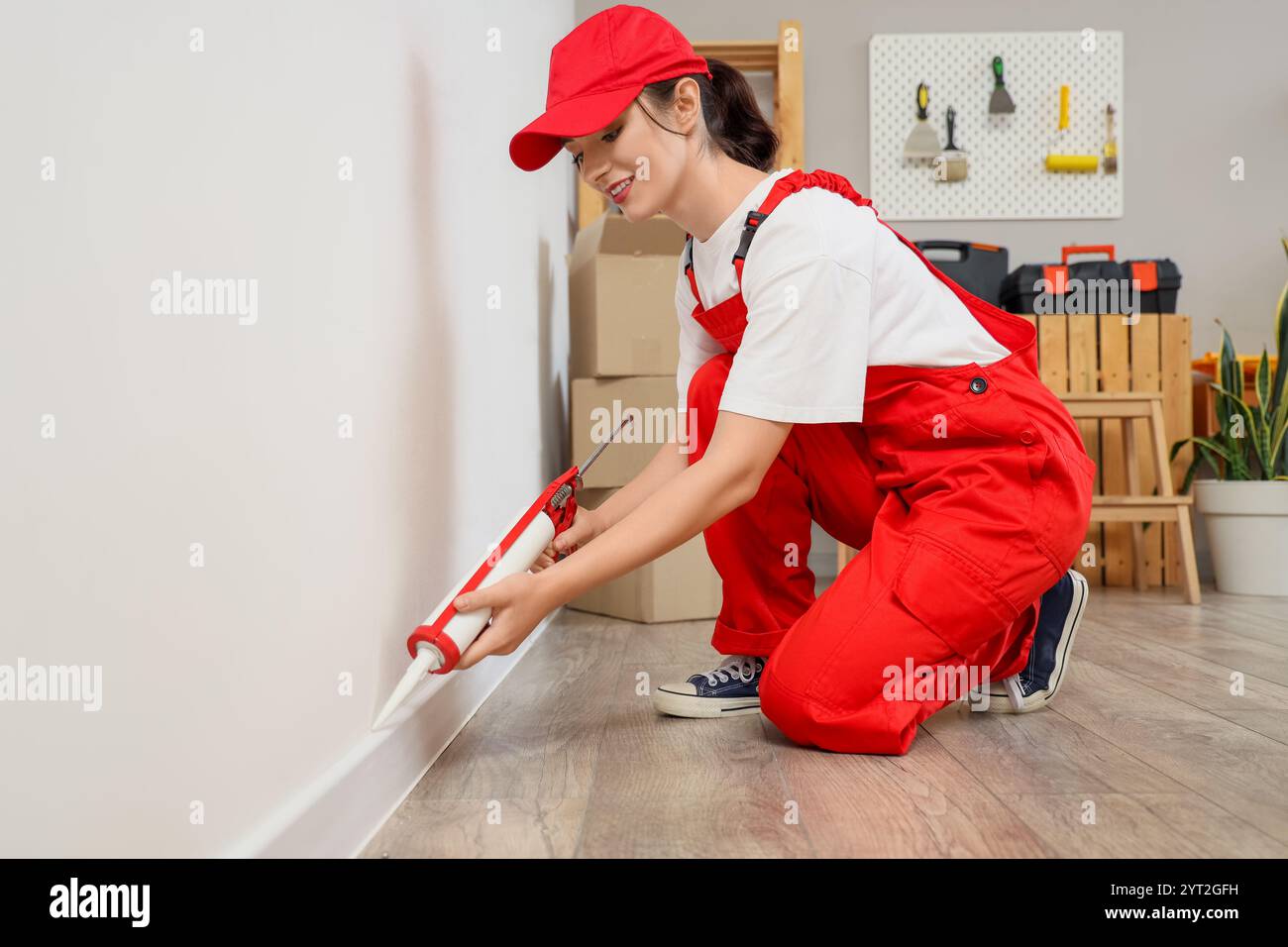 Female worker applying sealant to baseboard in room Stock Photo - Alamy