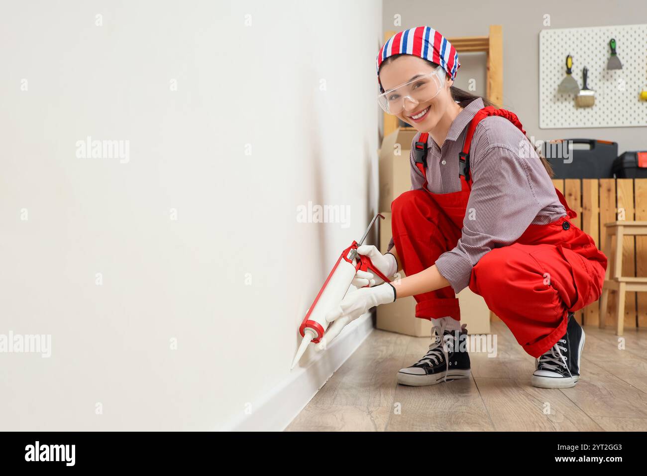 Female worker applying sealant to baseboard in room Stock Photo - Alamy