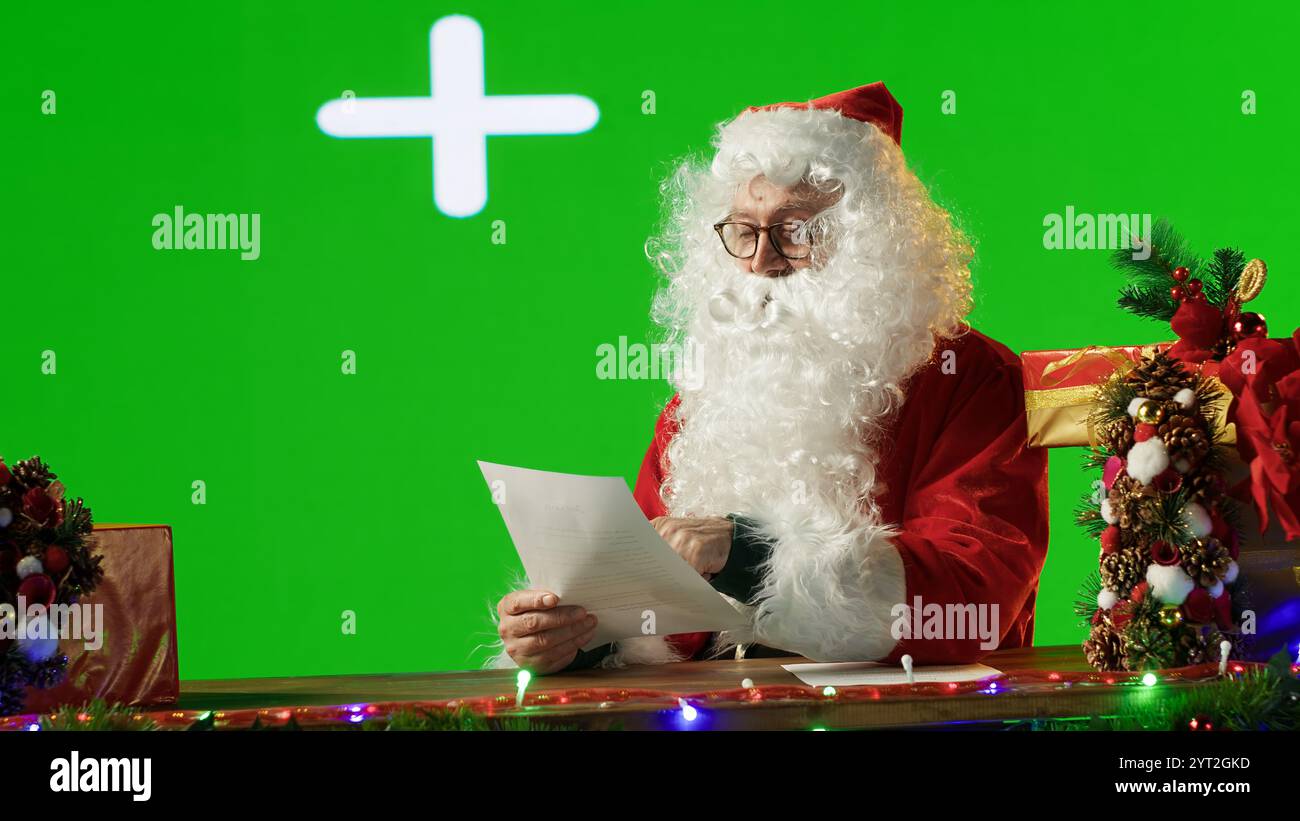 Santa sitting against isolated copy space screen and reading letters ...