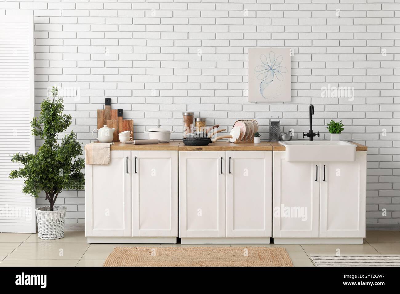 Folding screen and kitchen counter with utensils near white brick wall ...