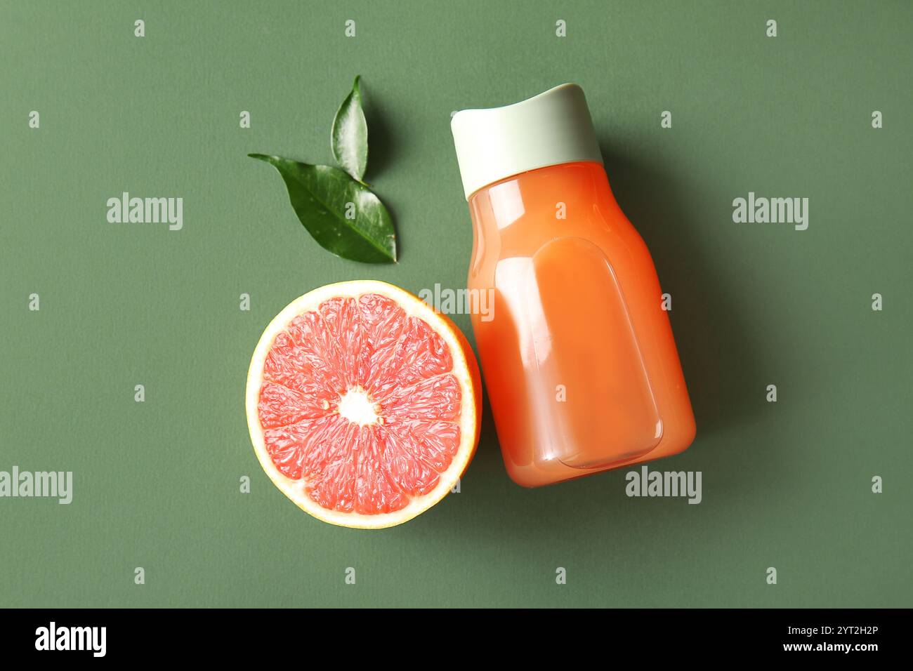 Bottle of tasty grapefruit juice and fresh fruit on green background ...