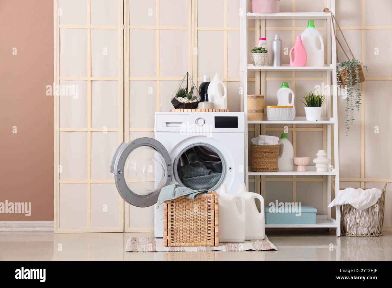 Interior of laundry room with folding screen, washing machine and shelf ...