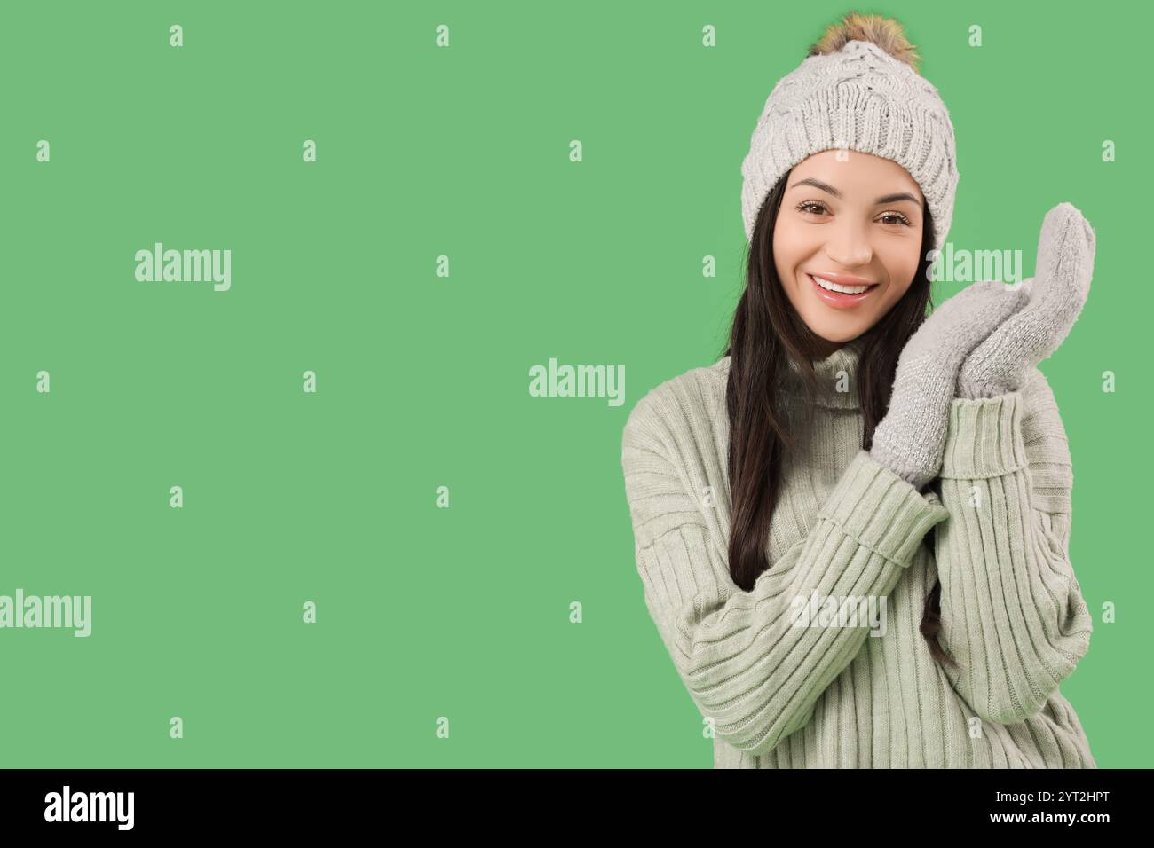 Frozen young woman in winter clothes on green background Stock Photo ...