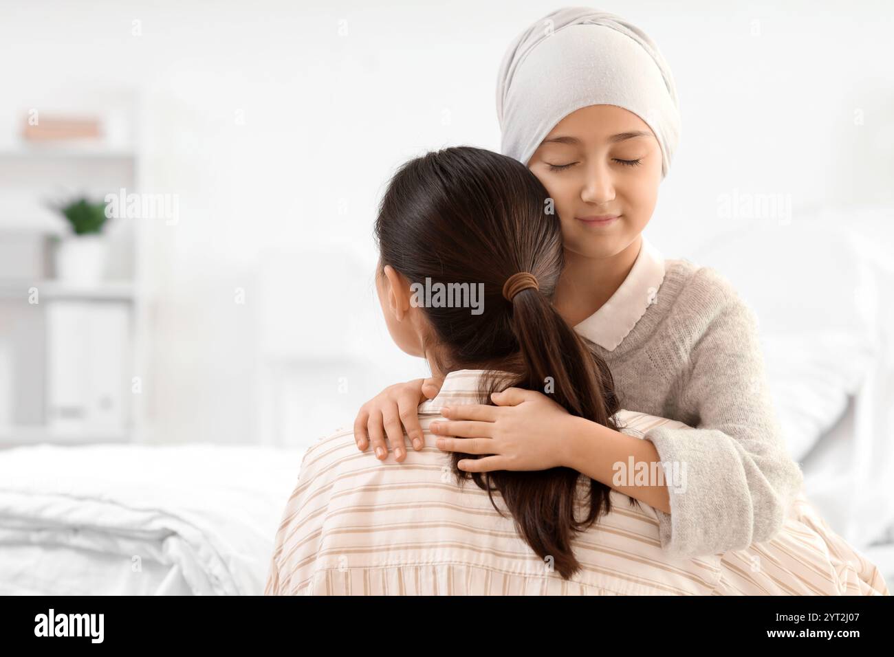 Little girl after chemotherapy hugging her mother in clinic. Childhood ...