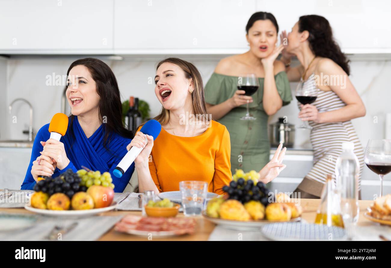 Group of female friends are having fun singing karaoke during feast and ...