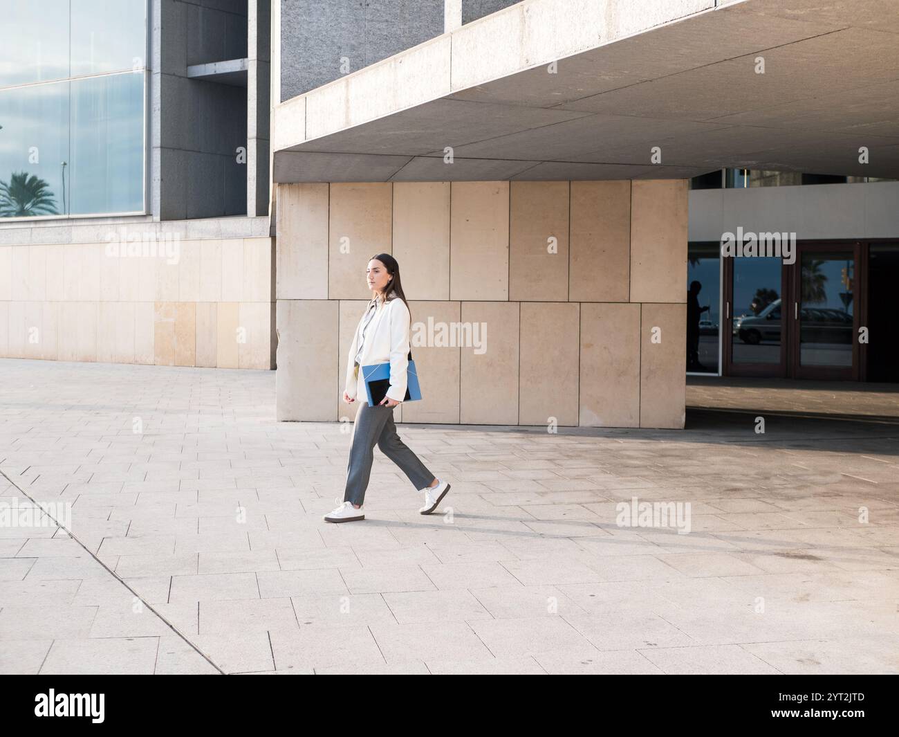 Young professional walking outside a modern office building with ...