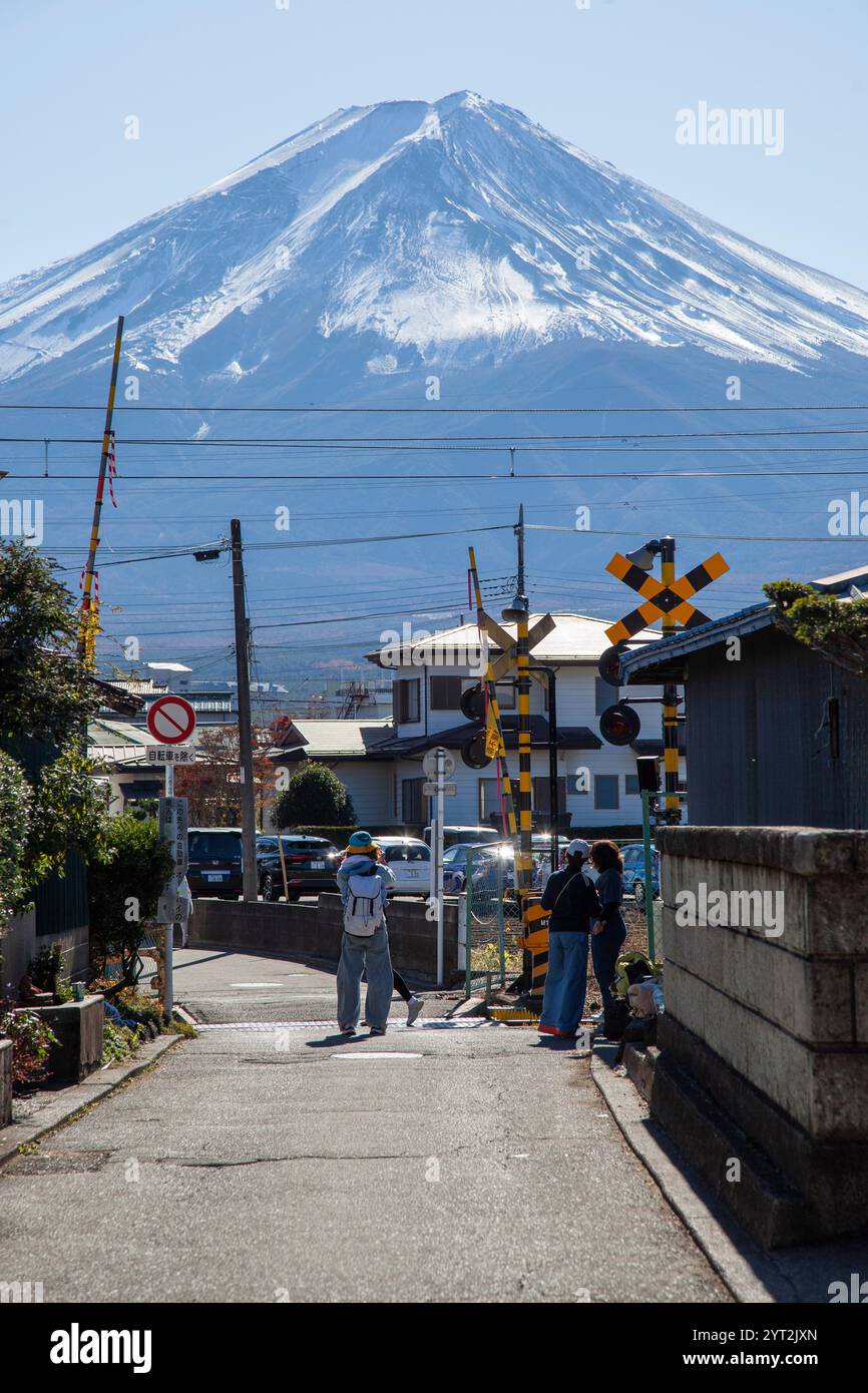Tourists on a small road and train crossing near Kawaguchiko Station in ...