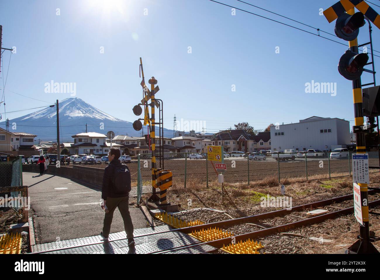 Tourists on a small road and train crossing near Kawaguchiko Station in ...