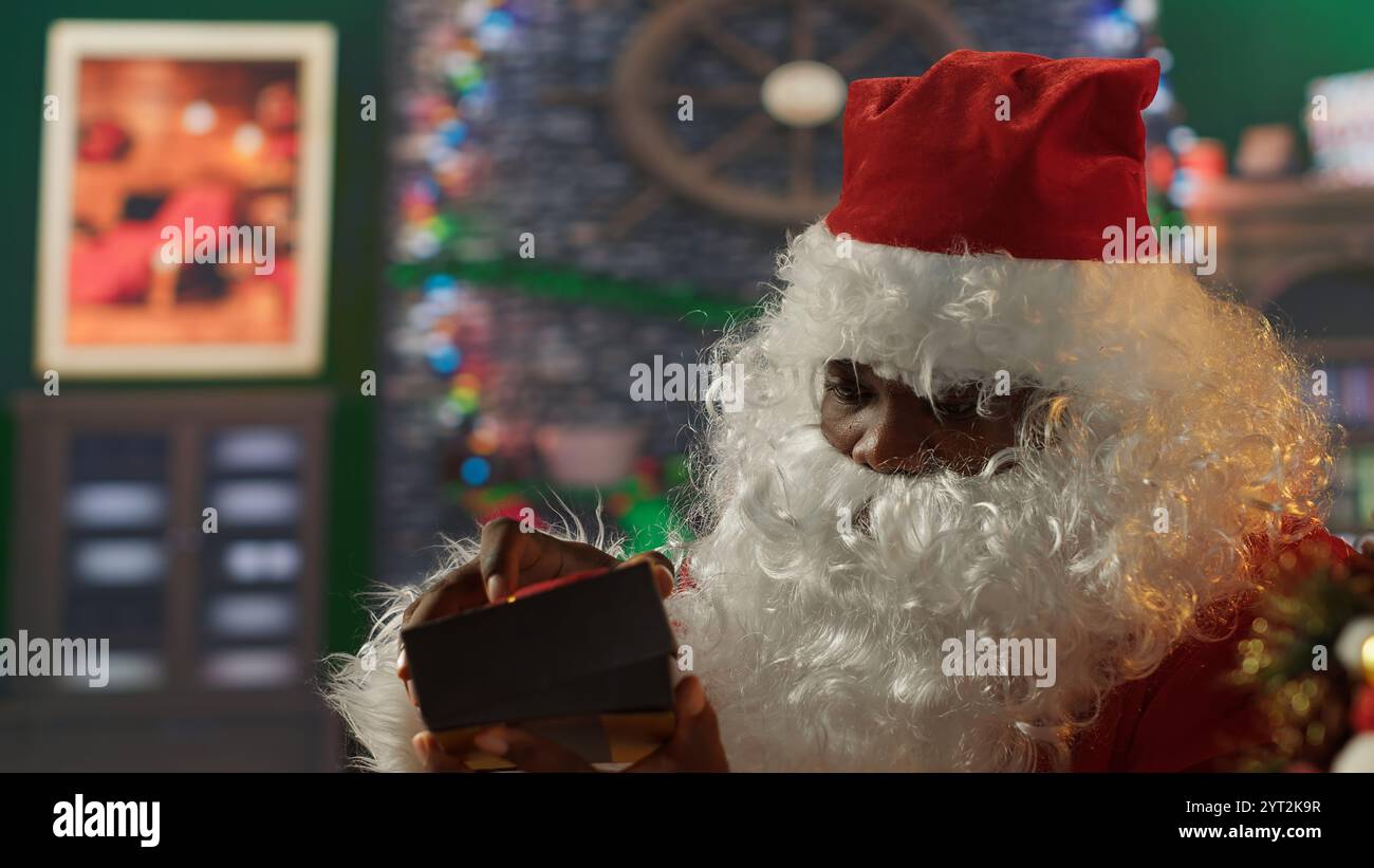 Black Santa wraps a festive gift box surrounded by Christmas lights and ...