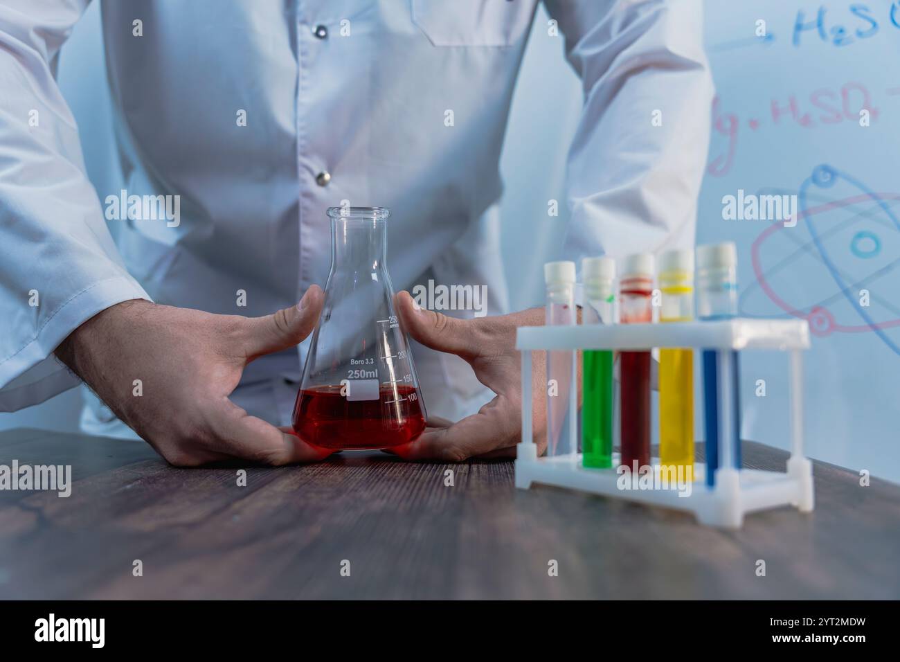 Close-up of a scientist handling a beaker with red liquid in a ...