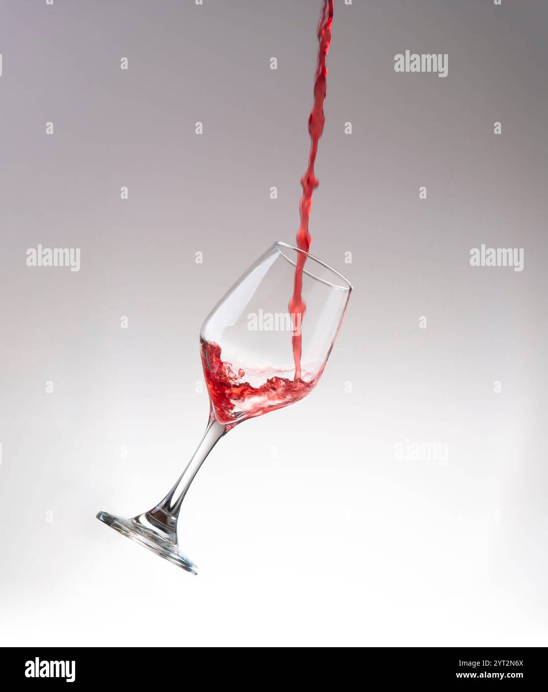 Front view of stream of red wine filling a crystal glass floating in ...