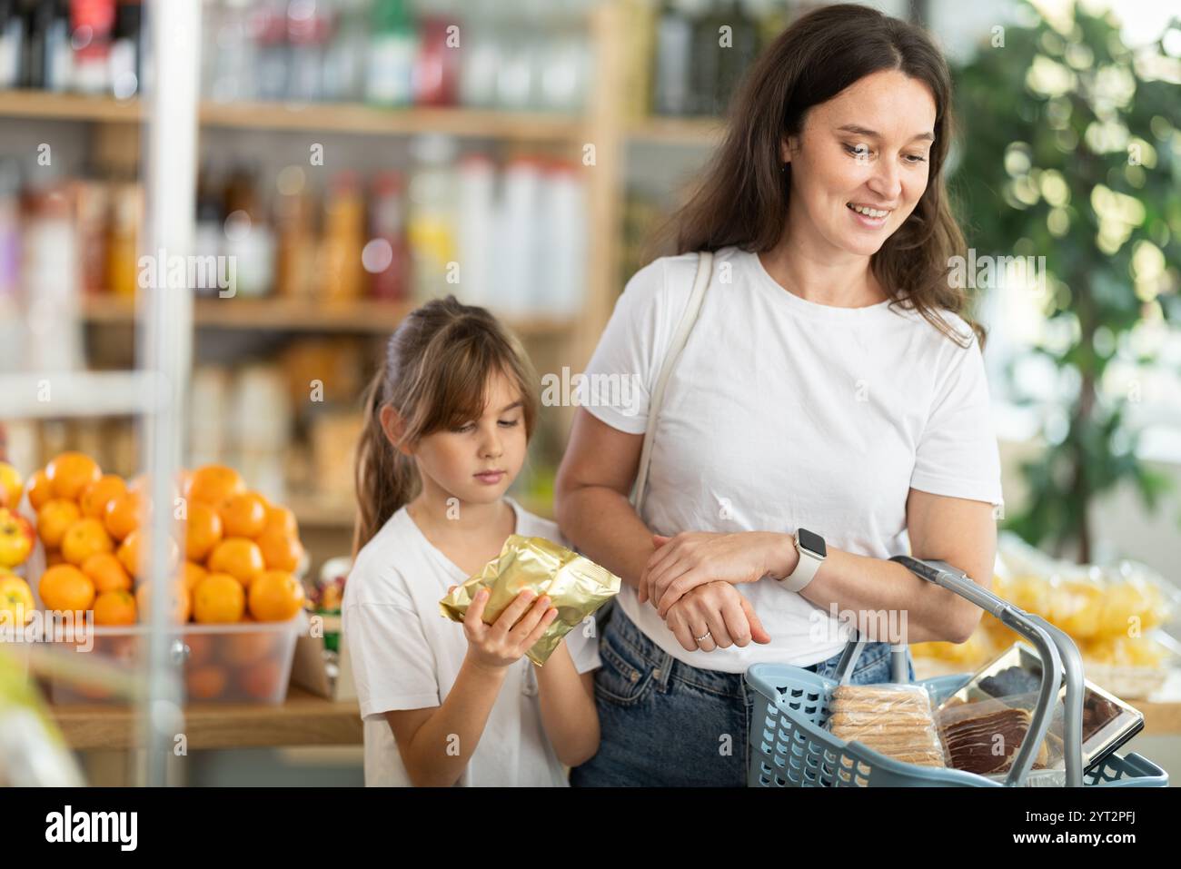 Visiting store, little girl and mom is looking at something on shelf of ...