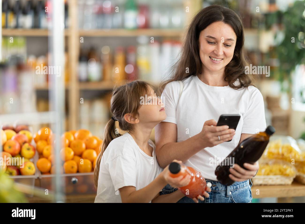 Mother and daughter choose bottles of juice and scan QR code with ...