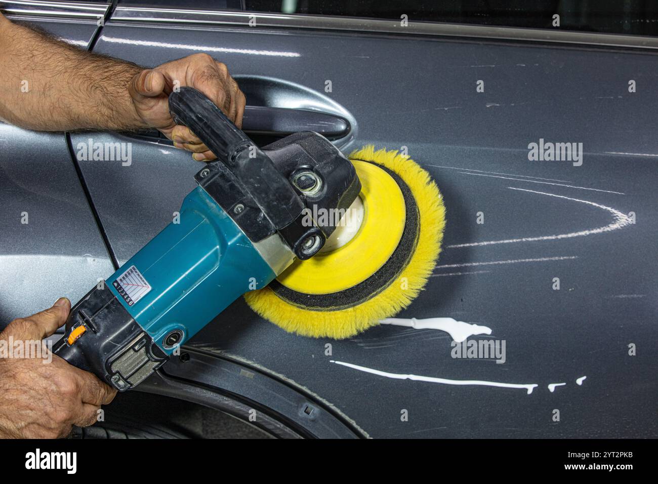 Professional car detailer holds air random orbital sander or dual ...