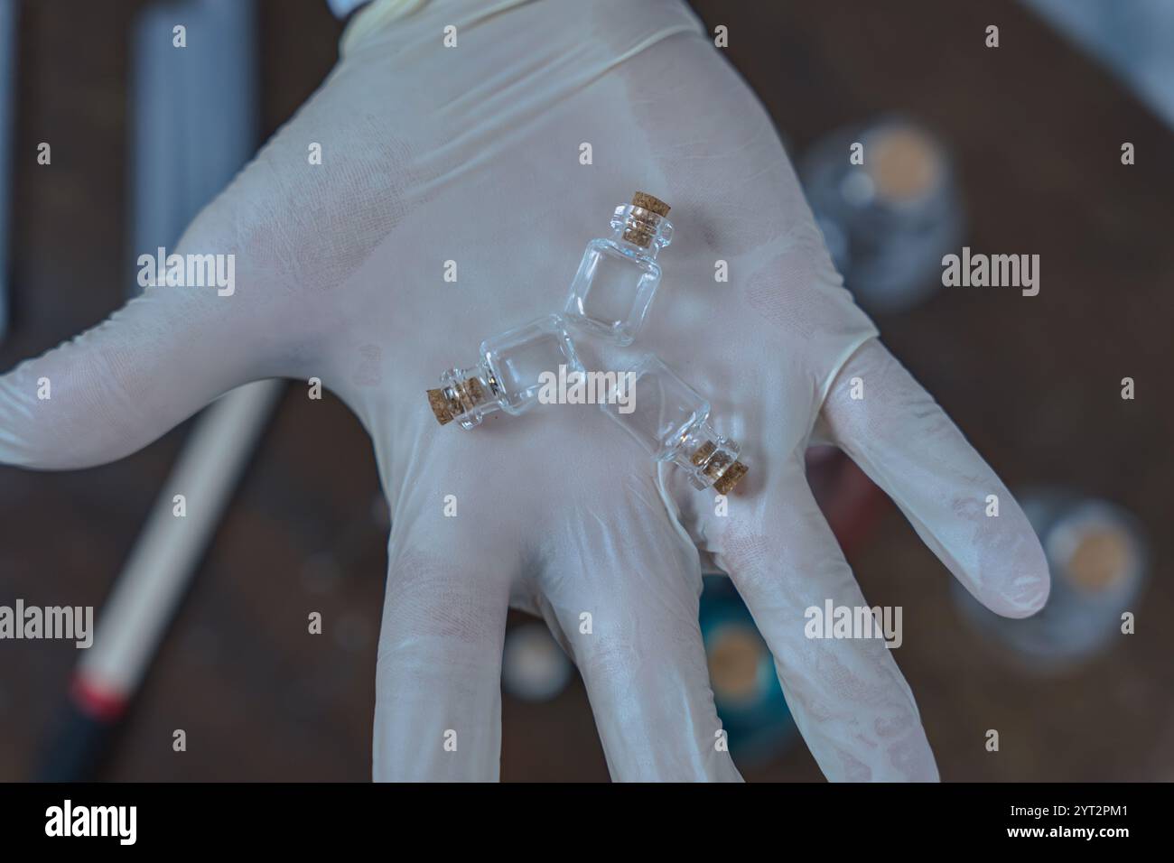 A gloved hand of a scientist holding small vials in a laboratory ...