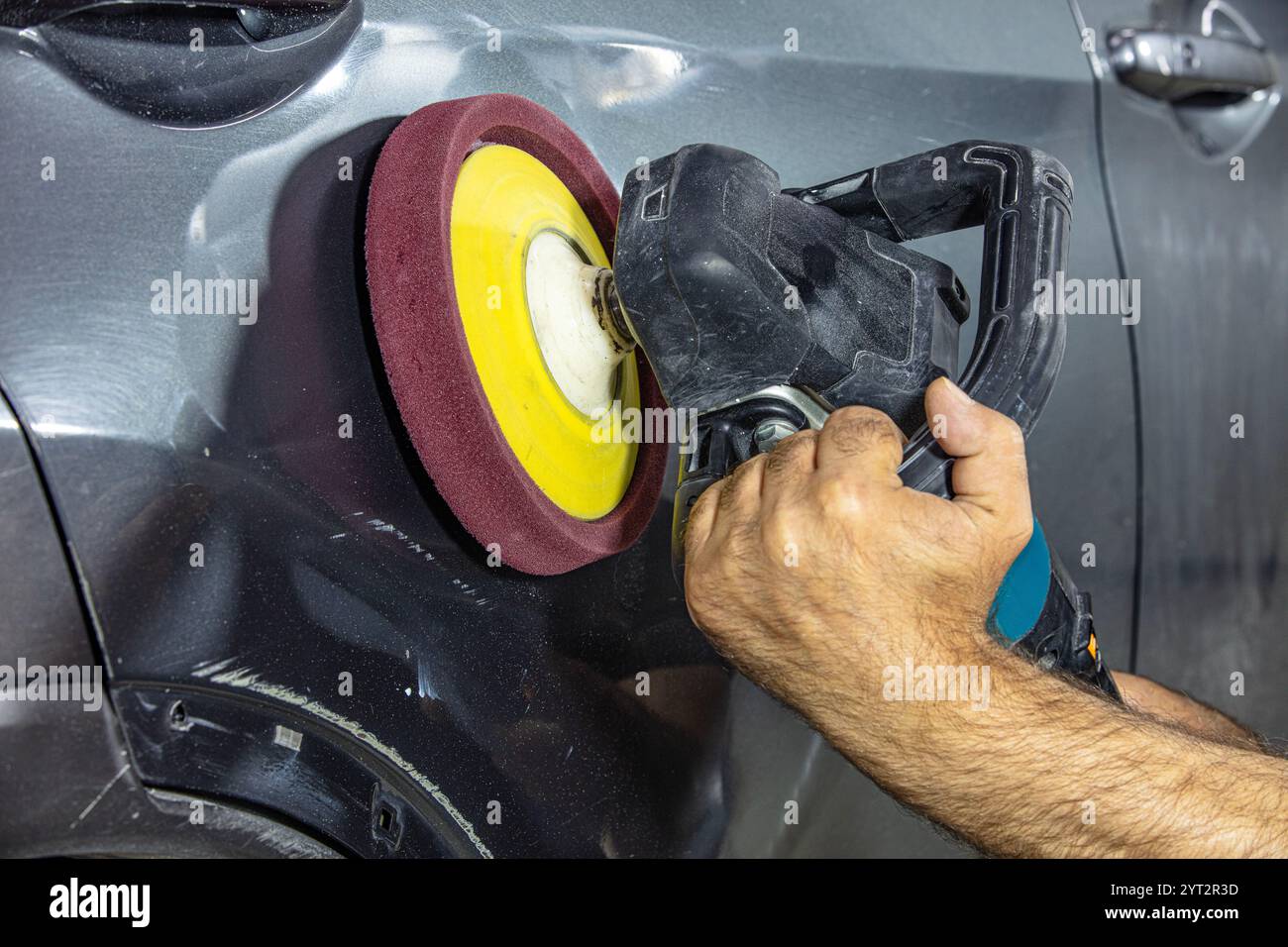 Professional car detailer holds air random orbital sander or dual ...