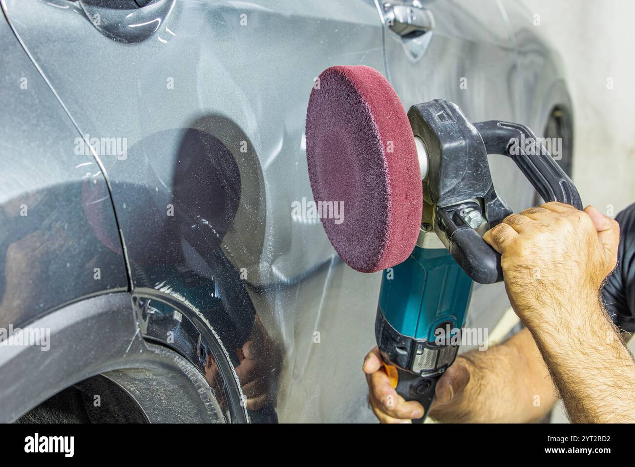 Professional car detailer holds air random orbital sander or dual ...