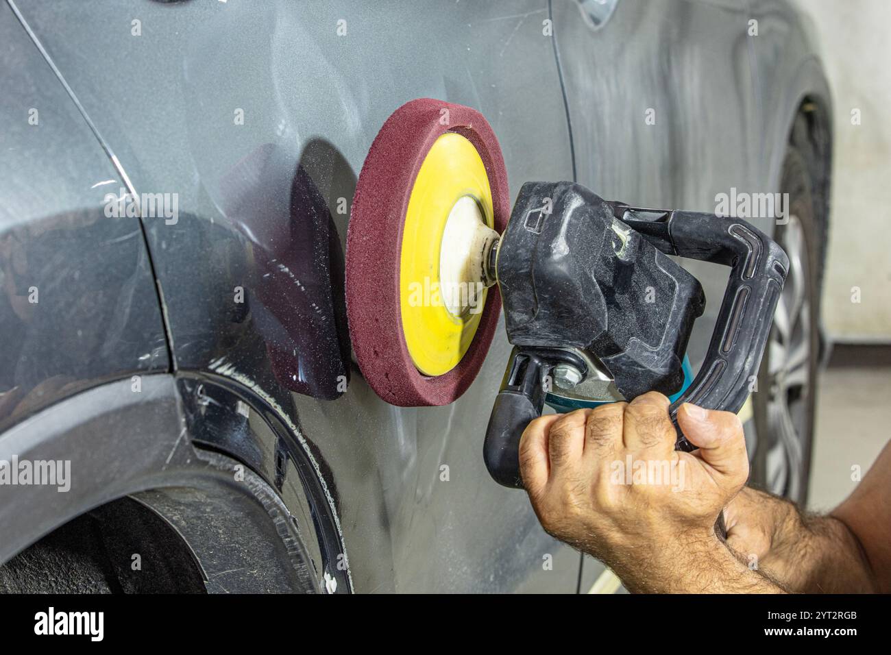 Professional car detailer holds air random orbital sander or dual ...